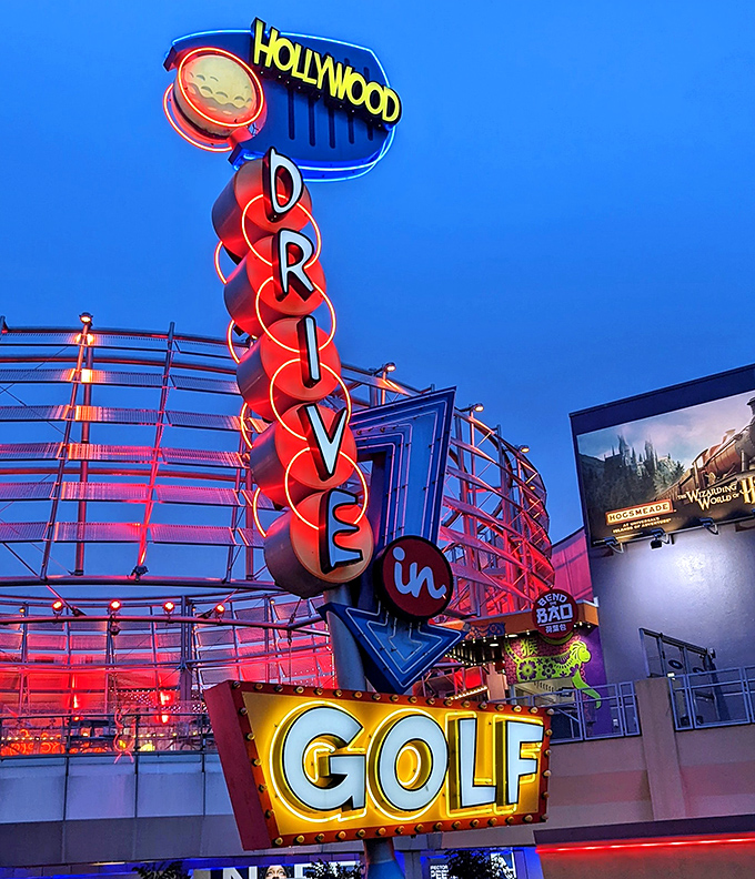 The iconic Hollywood Drive-In Golf sign glows brilliantly against the night sky, beckoning families to one last adventure before bedtime.