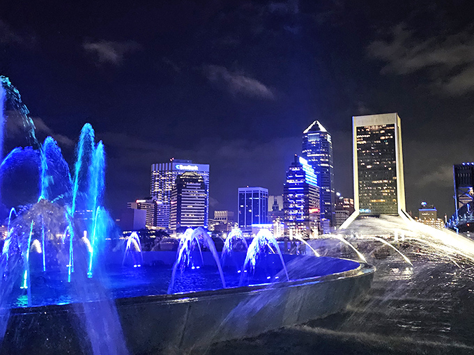 Friendship Fountain glows electric blue against Jacksonville's night skyline, creating a magical urban oasis where water dances with light.