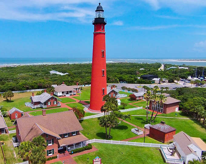 The towering red giant of Ponce Inlet stands proud against Florida's blue sky, a crimson sentinel watching over the coast for generations.