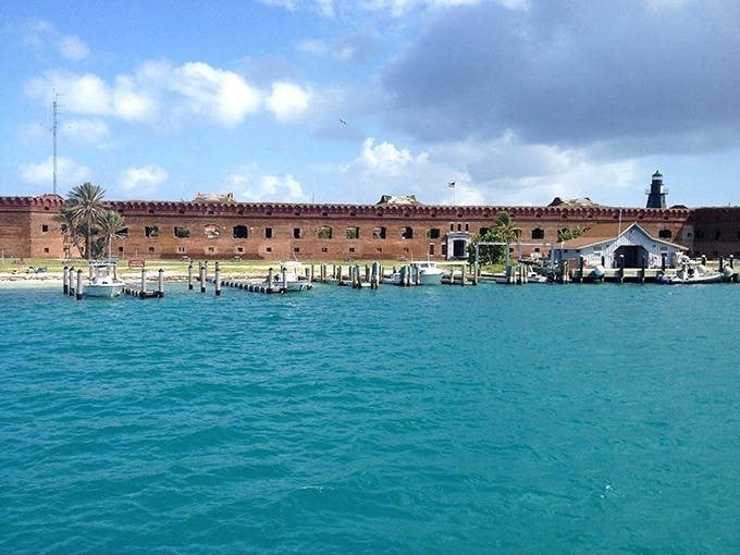 The impressive harbor view of Fort Jefferson showcases its grand scale, with boats docked alongside this brick giant that once guarded the Gulf of Mexico.