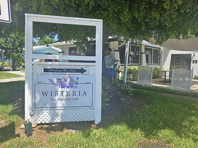 A welcoming entrance sign framed by trees invites tea lovers to "Porch This Way" into Wisteria's cozy world.