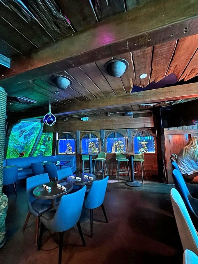 Blue lighting bathes the Wreck Bar's interior, creating an underwater atmosphere where aquariums glow between arched windows. The perfect spot for a magical evening escape.