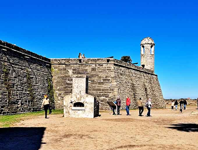 Visitors explore the fort's outer walls where Spanish sentries once watched for approaching British ships. No redcoats today, just red sunburns.