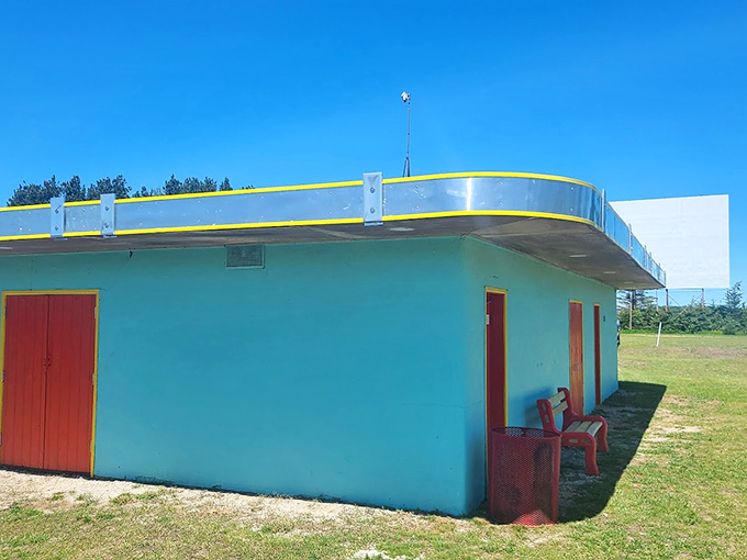 The teal concession building stands ready for intermission rushes, its red doors like portals to buttery popcorn paradise.