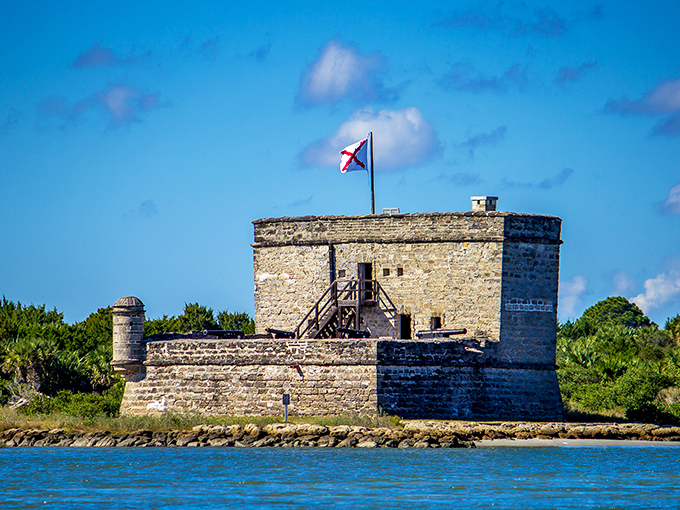 The coquina stone fortress rises from the marsh like a time traveler from colonial days, its flag announcing Spanish heritage to modern visitors.