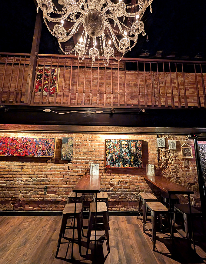 Interior: Crystal chandeliers illuminate exposed brick walls while wooden beams frame this time capsule where Prohibition-era elegance meets modern mixology magic.