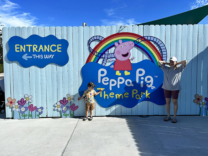 The entrance sign wall features cheerful blue fencing and colorful flowers – a perfect photo spot where excitement builds before the adventure begins.