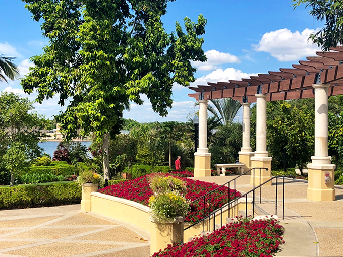 The pergola creates a dappled sanctuary from Florida's sunshine, where climbing vines form living architecture above garden wanderers seeking momentary shade.