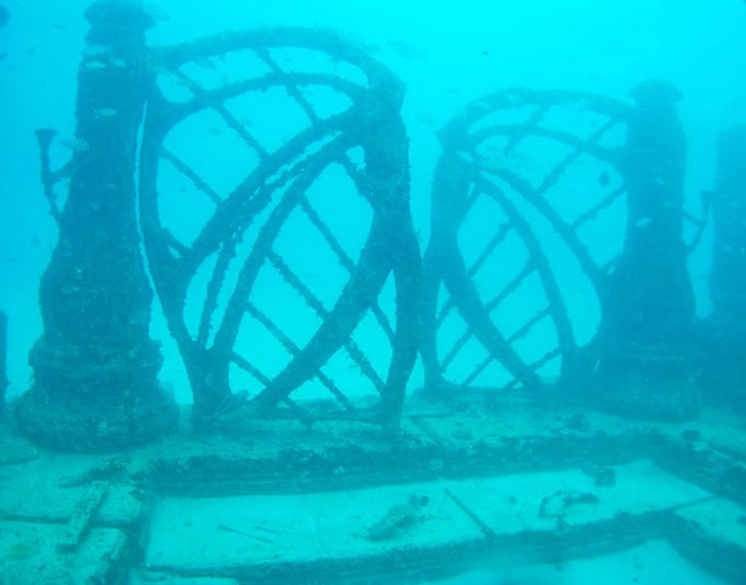 Intricate lattice structures form underwater archways, creating mysterious passages that beckon divers to explore their shadowy depths.