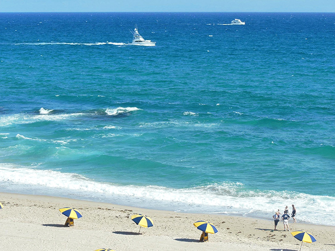 Beach bliss defined: crystal clear waters gently lap against the shore while boats drift lazily across the horizon.