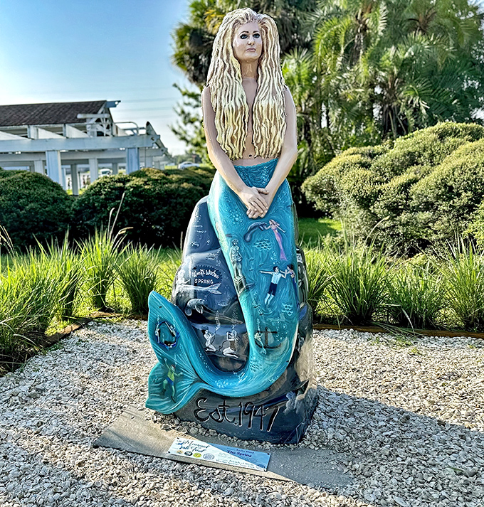This blue-tailed beauty gazes serenely from her perch, proving mermaids can rock the "established 1947" vintage look with effortless grace.