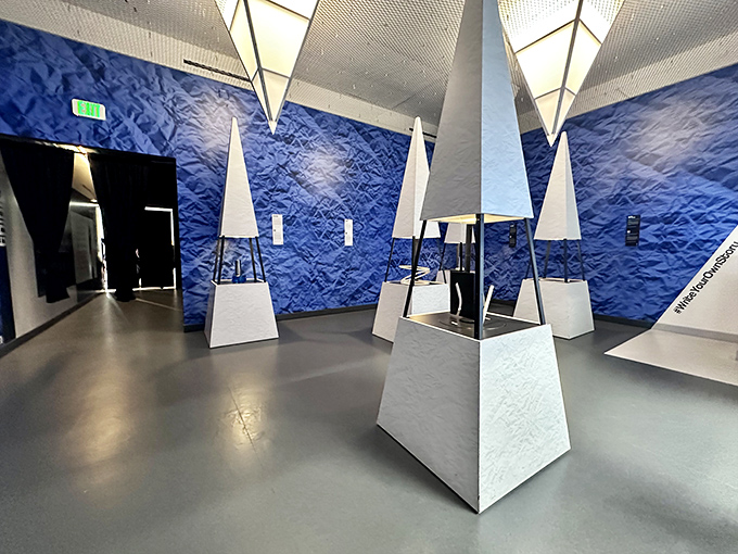 Blue walls and geometric white pyramids create an otherworldly corridor that makes you feel like you've stepped into a sci-fi movie set designed by a mathematician.