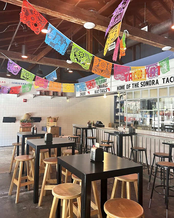Colorful papel picado banners dance overhead, transforming a simple space into a fiesta. The wooden beams whisper stories of tradition amid modern Miami.