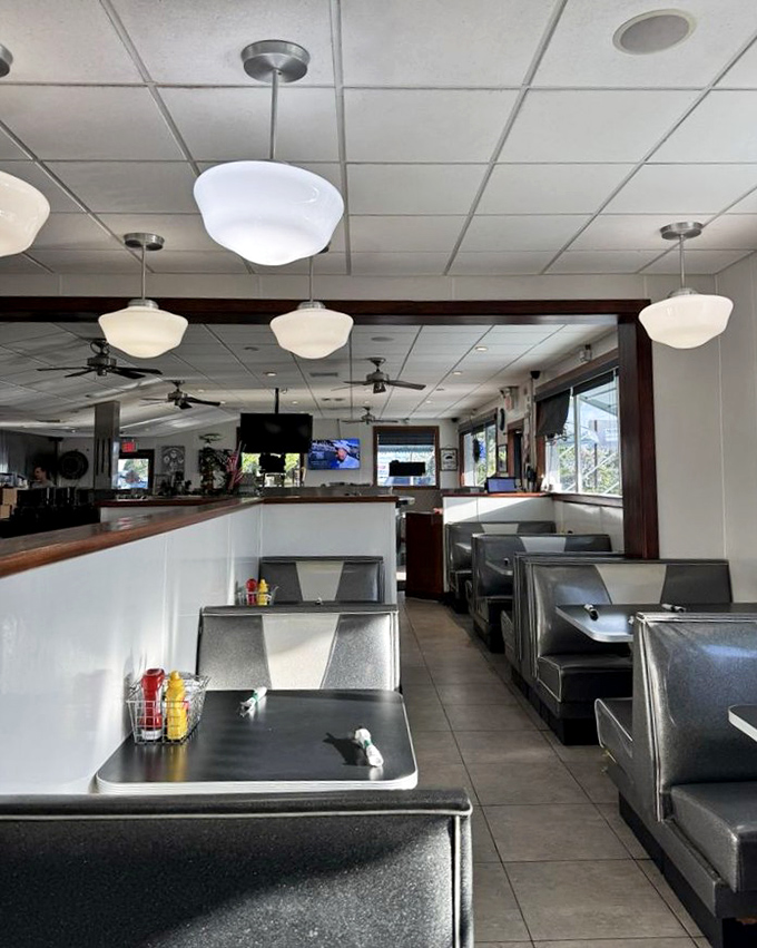 Classic diner booths gleam under schoolhouse pendant lights, creating the perfect backdrop for morning conversations and coffee refills.