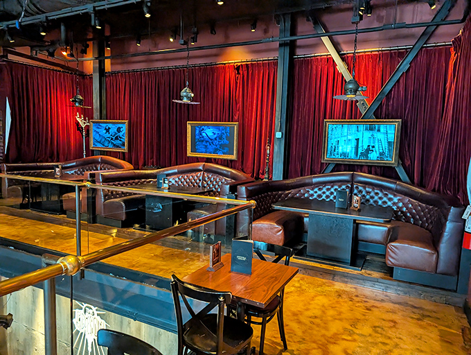 Rich burgundy curtains frame leather booths beneath industrial lighting, creating intimate dining nooks that feel like secret corners of a 1920s power plant.