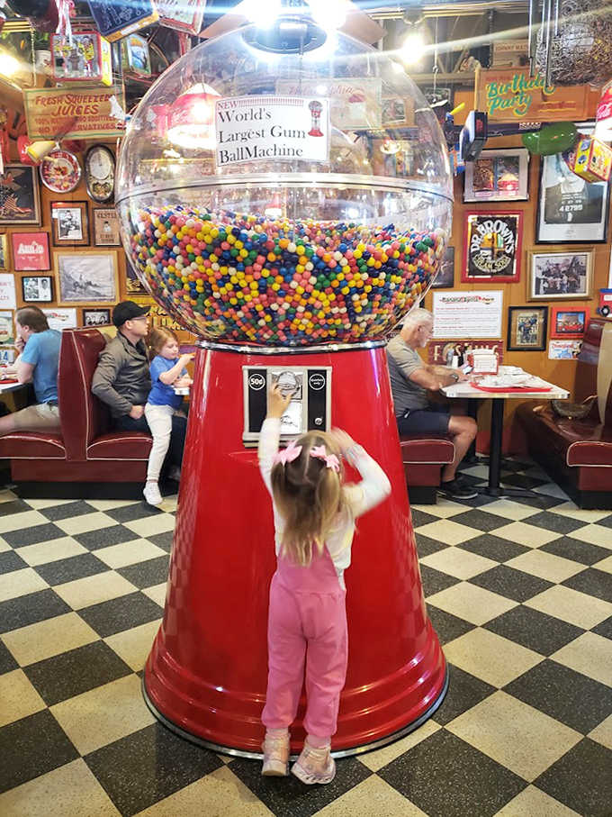 Children stand mesmerized by the world's largest gumball machine, a towering globe of colorful candies that captures the imagination and sweetens the atmosphere.