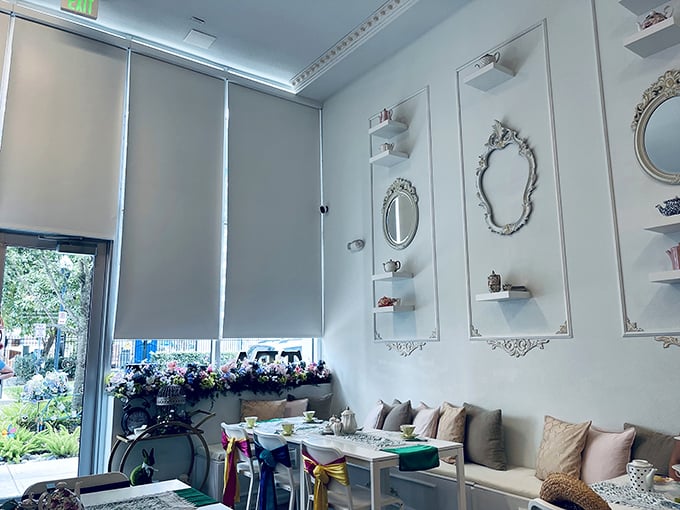 Inside, pristine white walls adorned with ornate mirrors create a bright sanctuary for afternoon tea indulgence.