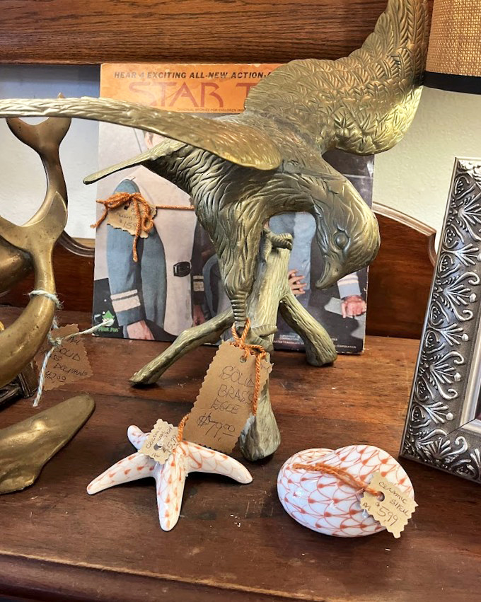 This majestic brass eagle sculpture stands guard over vintage treasures, its detailed feathers capturing the craftsmanship of a bygone era.