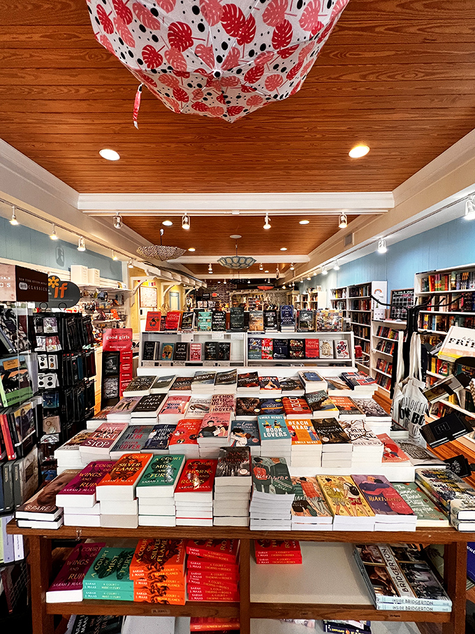 Colorful books create a rainbow of reading possibilities against calming blue walls, while fabric parasols add a touch of Mary Poppins-like whimsy overhead.