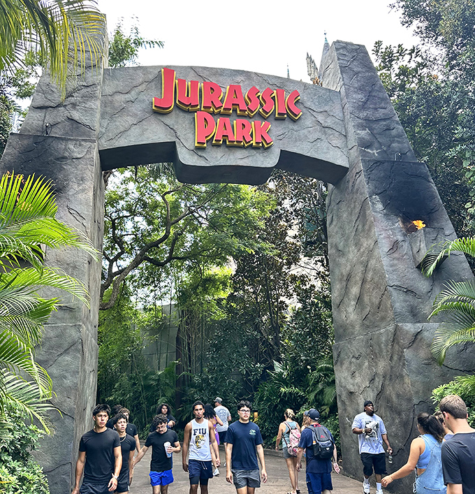 The iconic Jurassic Park gateway welcomes brave souls into a world where dinosaurs rule and humans are just fast food with opinions.