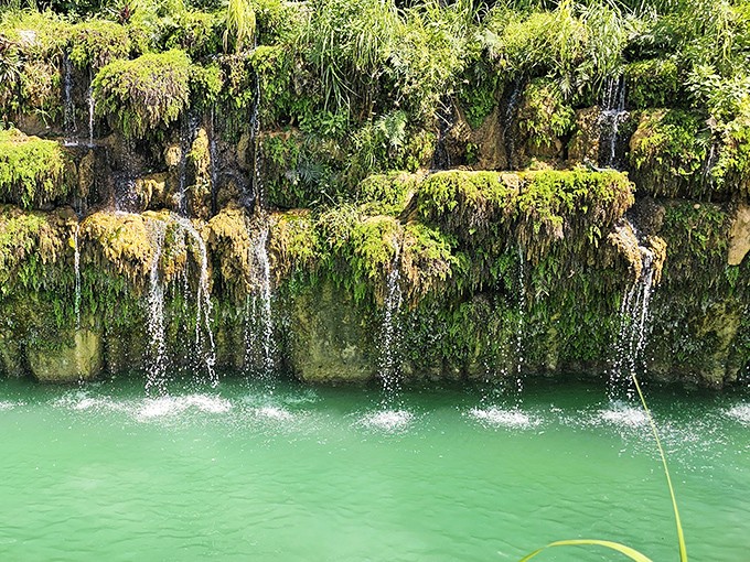 Nature meets artistry as water cascades down moss-covered rock walls, creating a soothing soundtrack that makes stress melt away instantly.