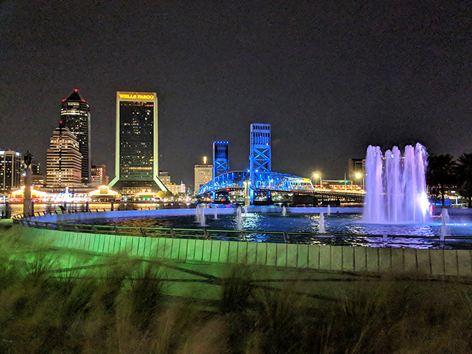 The nighttime transformation begins as Friendship Fountain's LED lights create a kaleidoscope effect against the darkening Jacksonville sky.