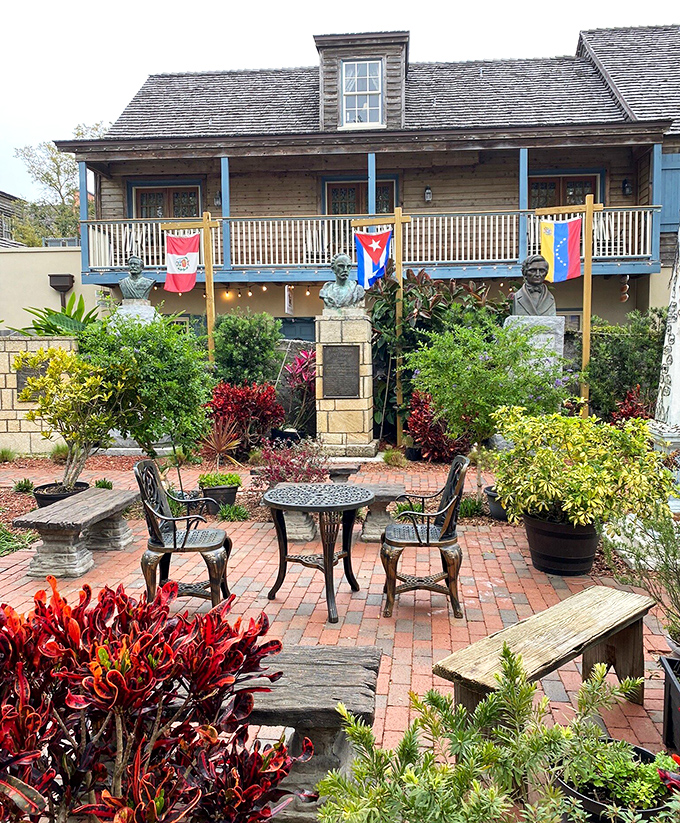 A peaceful courtyard where international flags flutter above stone benches, inviting contemplation beneath the watchful gaze of historical busts.