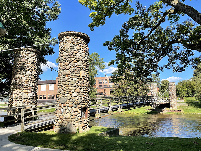 Stone pillars stand sentinel along the Shiawassee River, supporting a footbridge that looks like something from a storybook illustration.
