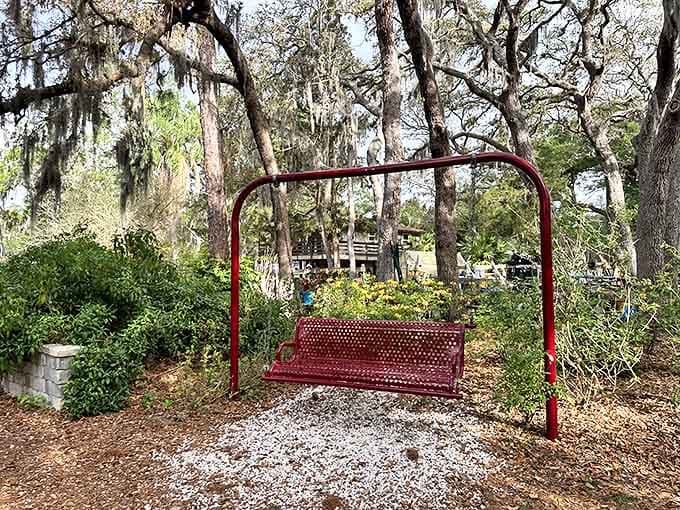 This charming red swing invites visitors to pause and sway gently beneath ancient oaks, a simple pleasure that feels like childhood rediscovered.