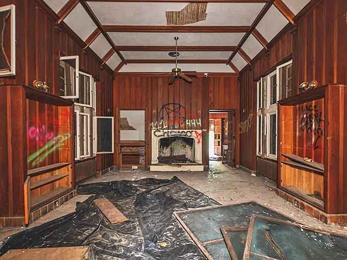 Wood-paneled walls that once hosted society's elite now serve as canvas for modern expression, sunlight streaming through broken windows.