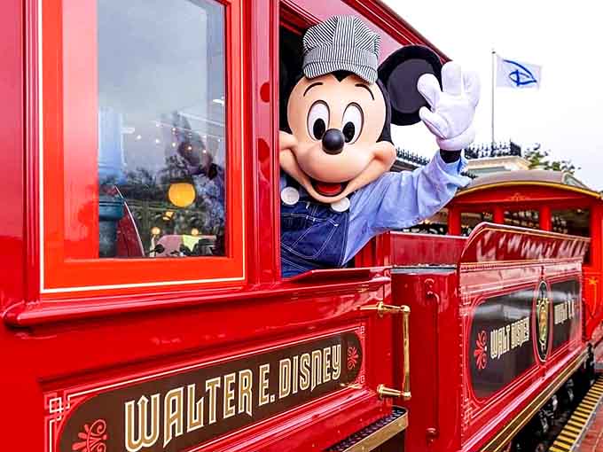 Mickey Mouse, dressed in classic engineer overalls, waves to guests from the Walter E. Disney locomotive &ndash; a magical moment that bridges generations.