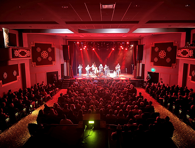 A full house bathes in red light as performers command the stage &ndash; is that a shadowy figure watching from the upper balcony?
