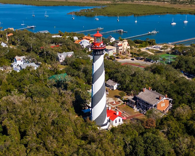 St. Augustine's iconic black and white spiral lighthouse rises dramatically against puffy clouds, its distinctive pattern a navigational landmark for centuries.