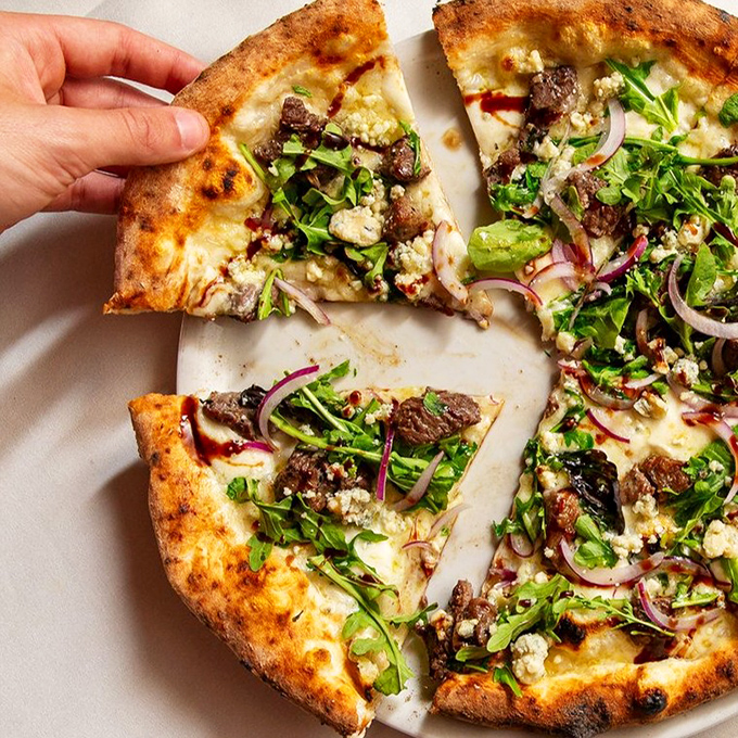The Bistecca Pizza emerges from a 700-degree brick oven, topped with tender filet mignon that might make you forget you came for the drinks.