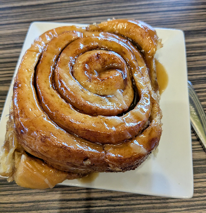 This cinnamon roll isn't just breakfast; it's an architectural marvel of spiraled dough with frosting applied so generously it borders on philanthropy.