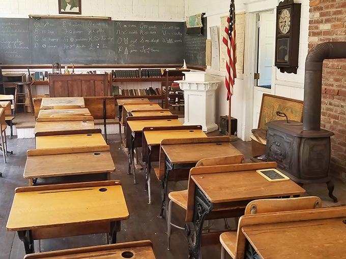 Wooden desks await phantom students, the potbellied stove ready to warm young minds. No Wi-Fi password needed in this learning space.