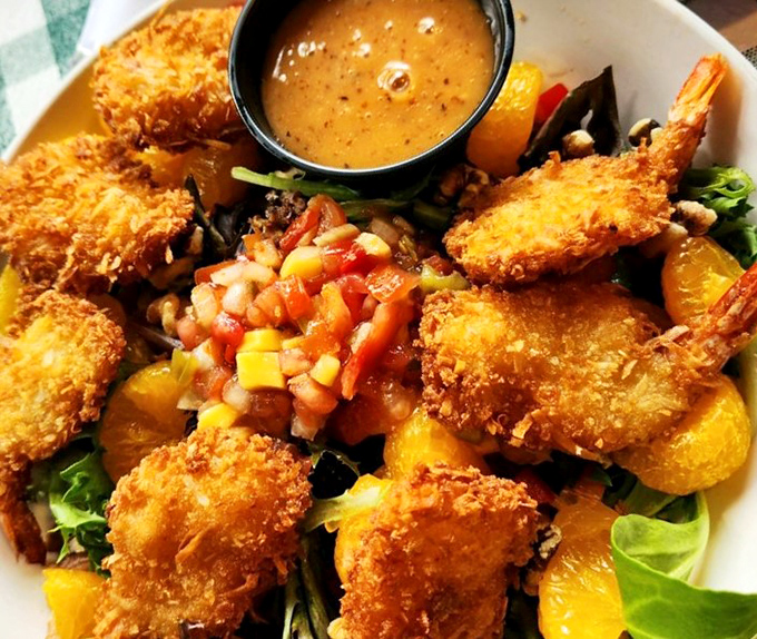 Golden-brown coconut shrimp perch atop a vibrant salad like tropical treasures, proving Linger Lodge's food is as impressive as its decor.