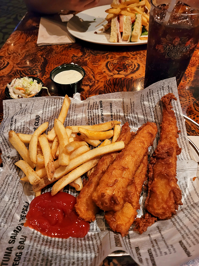 Golden-fried fish and crispy fries arrive newspaper-style, a nod to British tradition that somehow works perfectly in this tropical setting.
