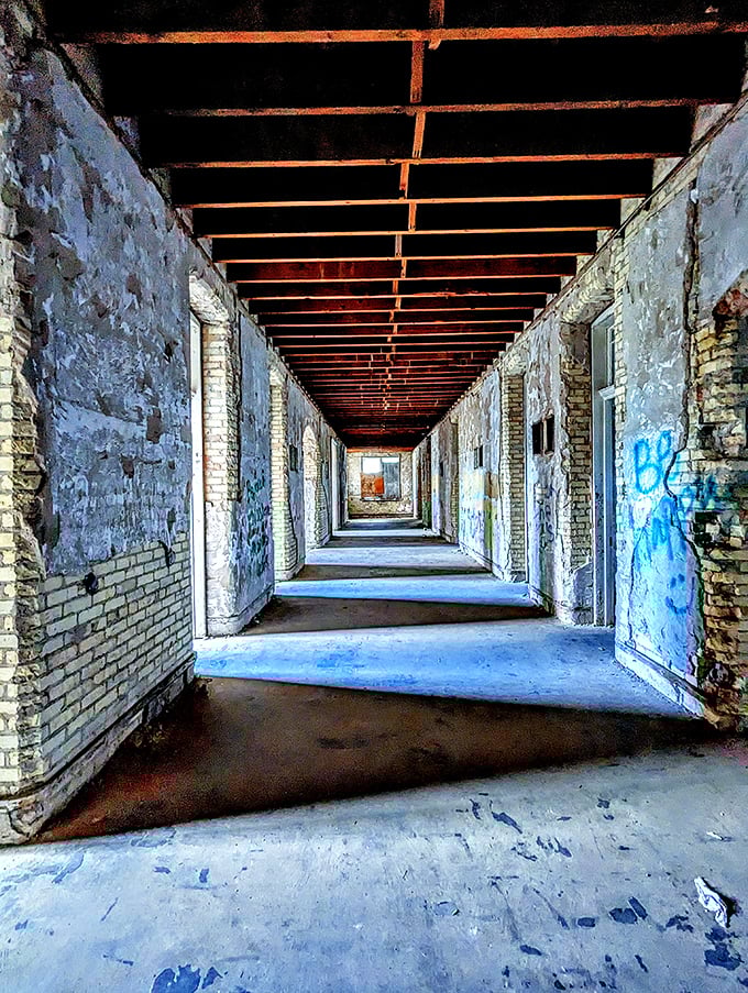 Abandoned corridors stretch toward vanishing points, telling silent stories of countless footsteps that once echoed through these institutional passageways.