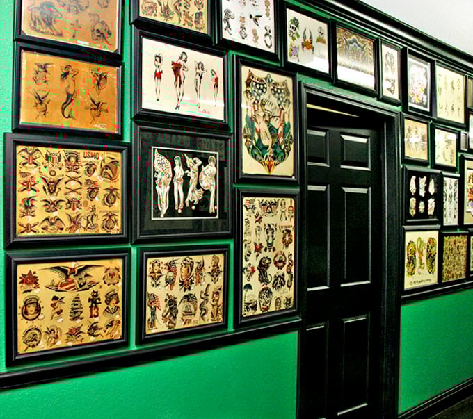 The green walls provide a striking backdrop for vintage tattoo designs, creating a gallery-like atmosphere for this folk art.