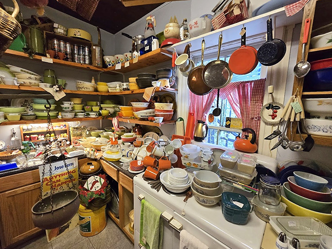 The kitchen area overflows with colorful vintage cookware &ndash; Pyrex bowls, cast iron pans, and utensils that have stirred countless family meals.
