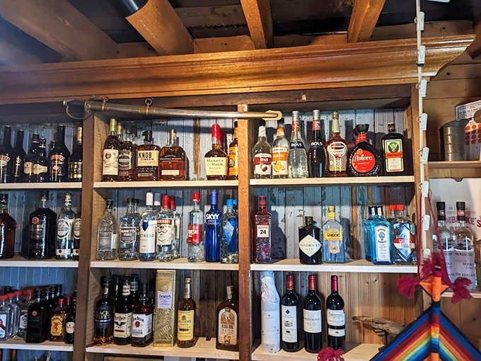 The liquor selection spans from everyday essentials to small-batch treasures, arranged on wooden shelves like a library of spirits waiting to tell their stories.