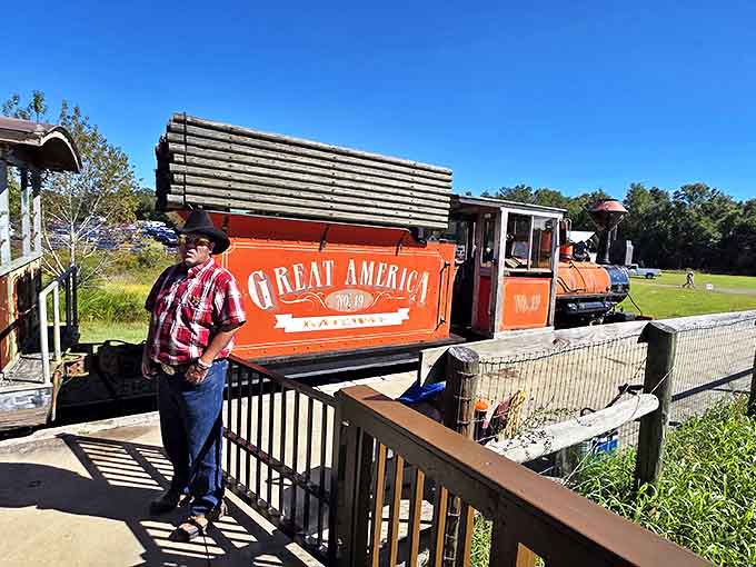 A railroad enthusiast stands proudly beside the Great America locomotive, his passion for preservation evident in every carefully maintained detail.