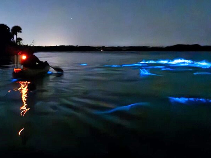 A lone kayaker creates cosmic ripples in the darkness, proving you don't need special effects when Mother Nature's got the controls.