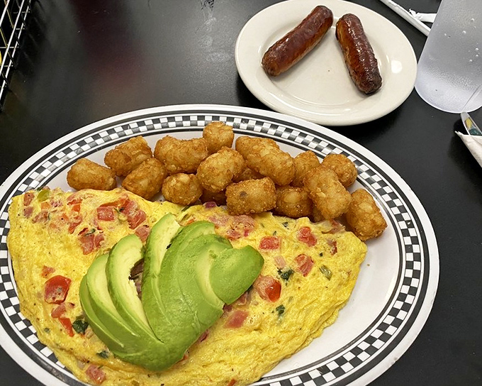 This isn't just any omelet – it's a masterclass in egg architecture, stuffed with fresh ingredients and paired with golden tater tots.