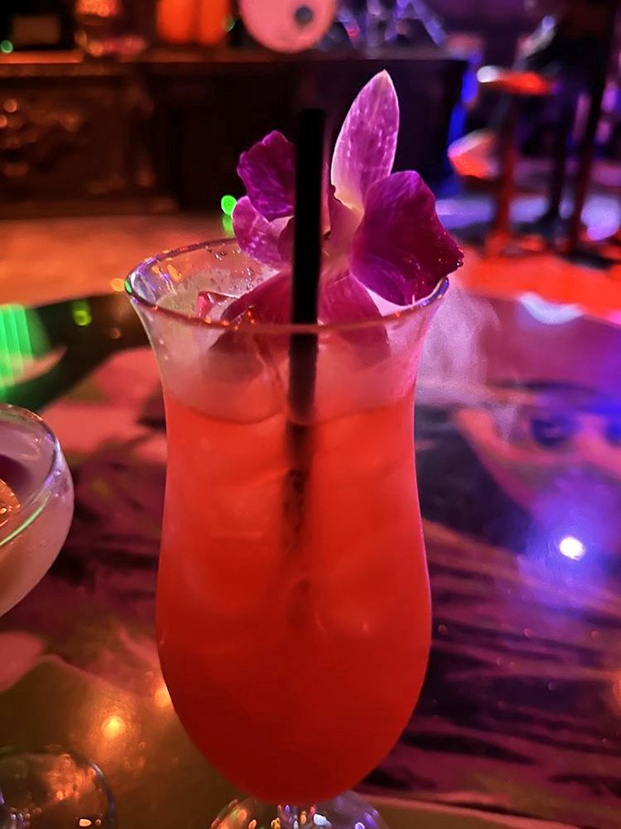 The "Scarlet Fever" cocktail glows an enticing red, garnished with a vibrant orchid &ndash; proof that at Cocktails & Screams, even your drinks dress up for the occasion.