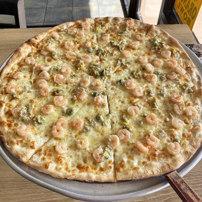 This seafood masterpiece features plump shrimp scattered across a garlicky white canvas &ndash; like the ocean decided to vacation on your pizza.