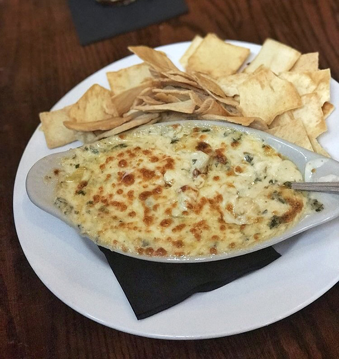 The legendary spinach artichoke dip arrives bubbling hot, its golden top giving way to a creamy treasure that's worth every calorie.