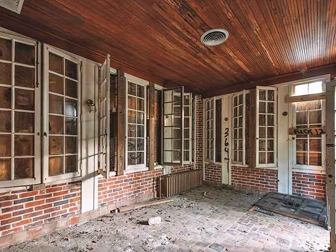 The sunroom's brick and glass design once brought controlled nature indoors &ndash; now the boundary blurs as wilderness reclaims its territory.