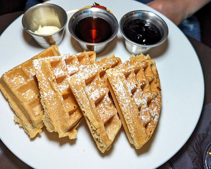 Golden waffles dusted with powdered sugar&mdash;breakfast's greatest hit making a surprise appearance at dinner. Three dipping sauces because choosing is overrated.